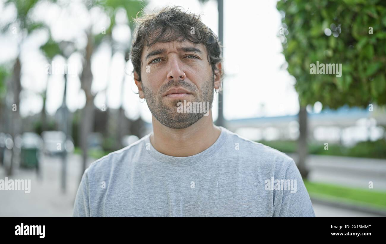 Confident young man with a serious expression, standing in an urban ...