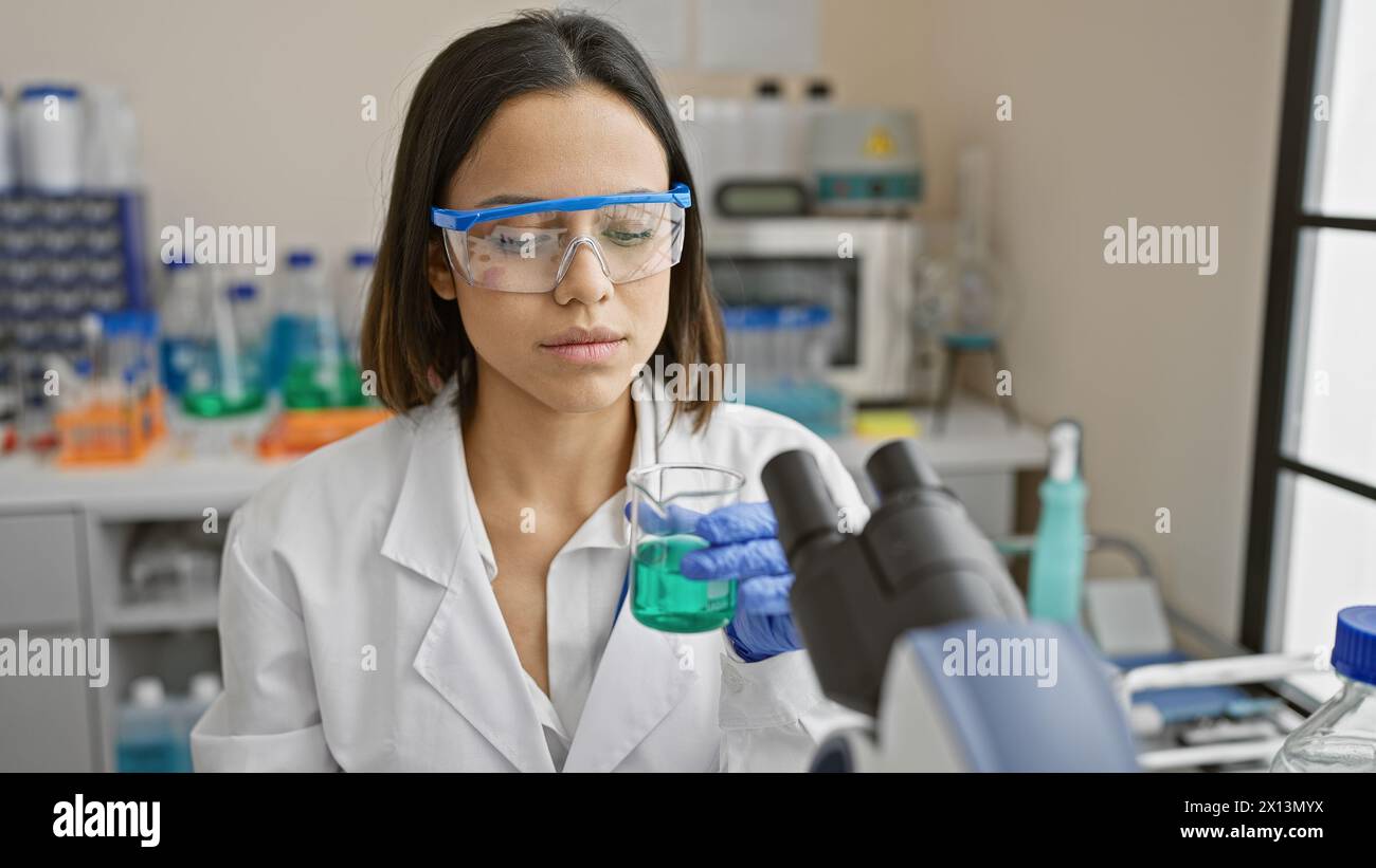 Focused hispanic woman scientist analyzing a chemical sample in a ...