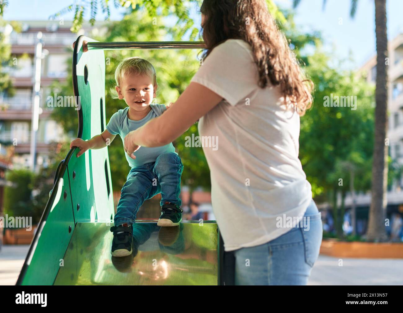 Mother and son smiling confident playing on slide at park playground Stock Photo - Alamy