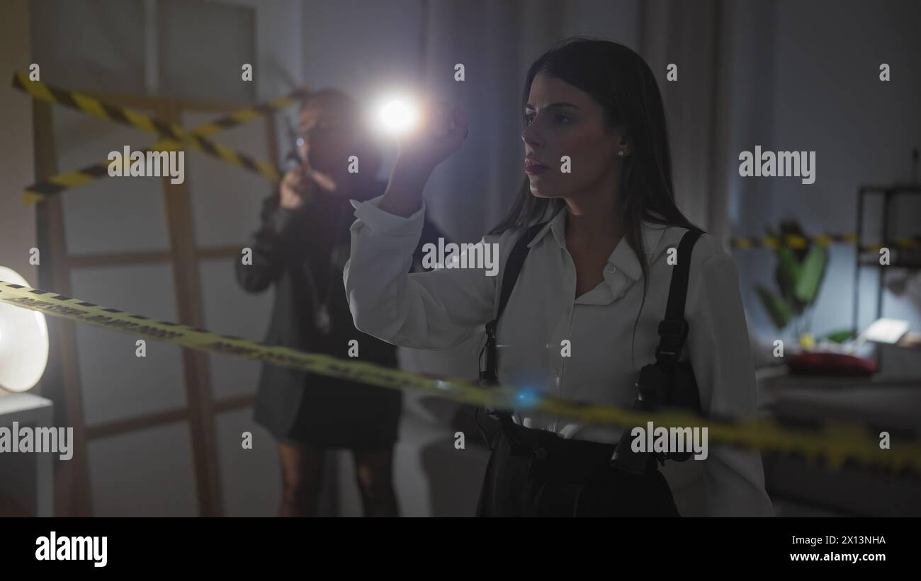 Two women investigators analyzing a crime scene indoors with flashlight ...