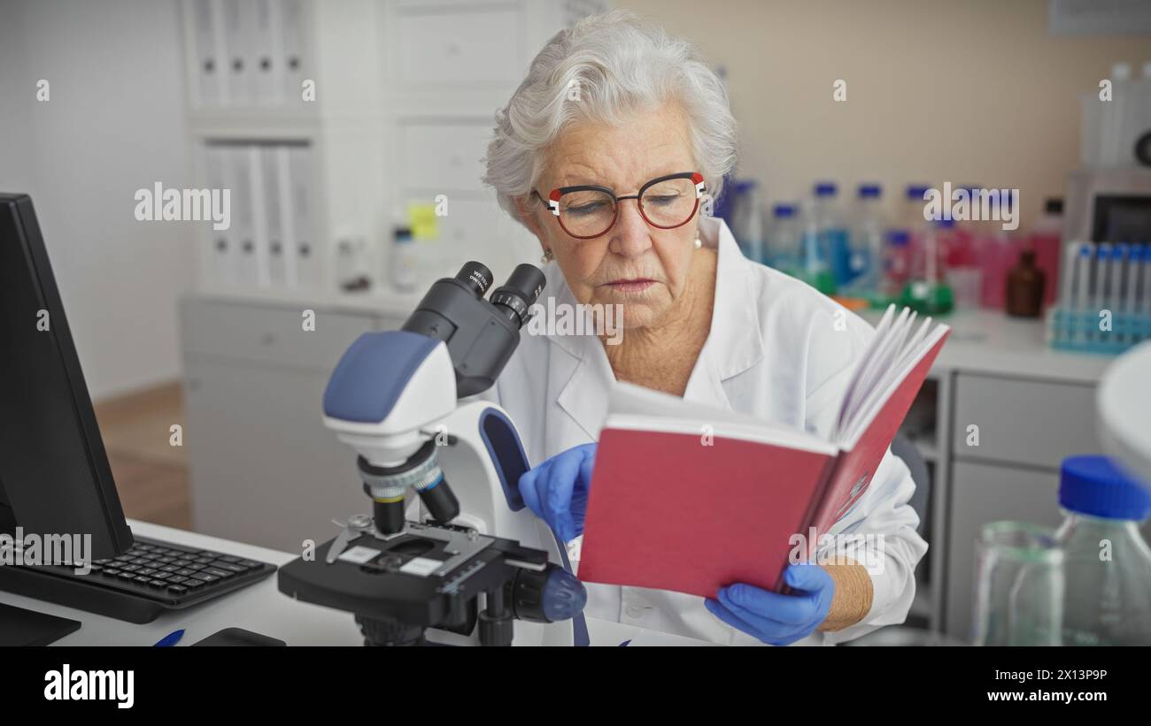 Senior woman scientist reading a book while working with a microscope ...