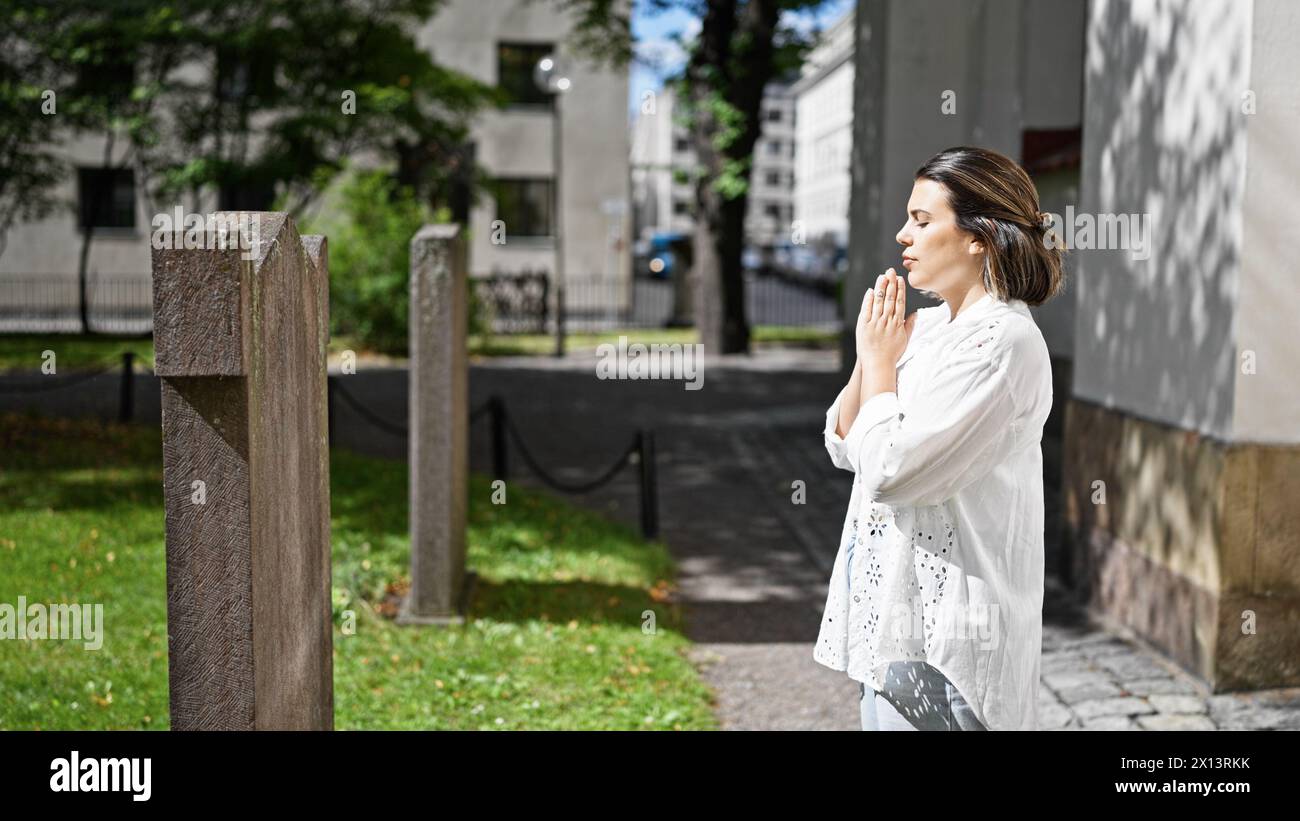 Beautiful young hispanic woman praying and mourning by tombstone at ...