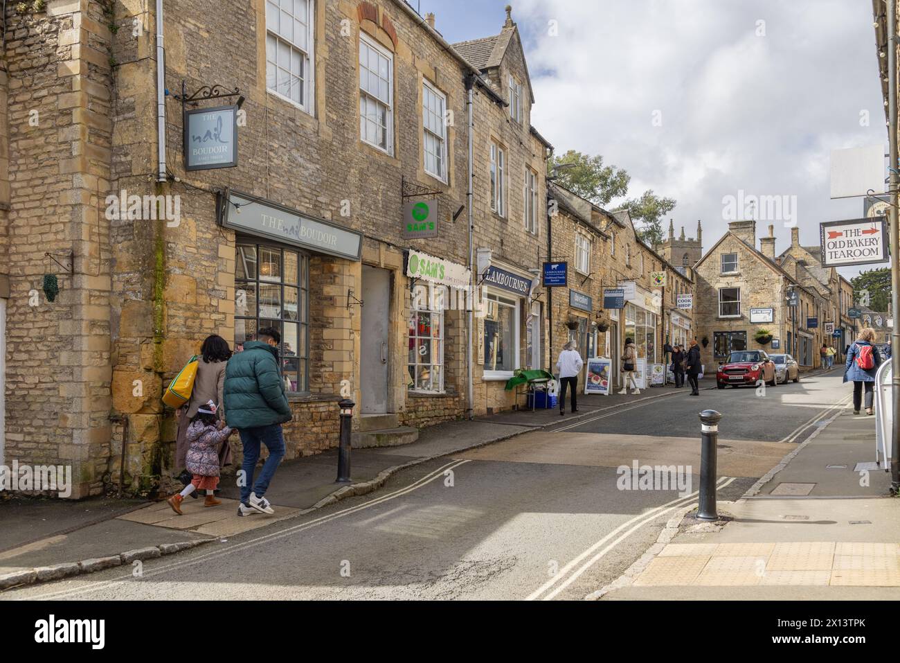 Tourists and shoppers strolling along a street lined with honey ...