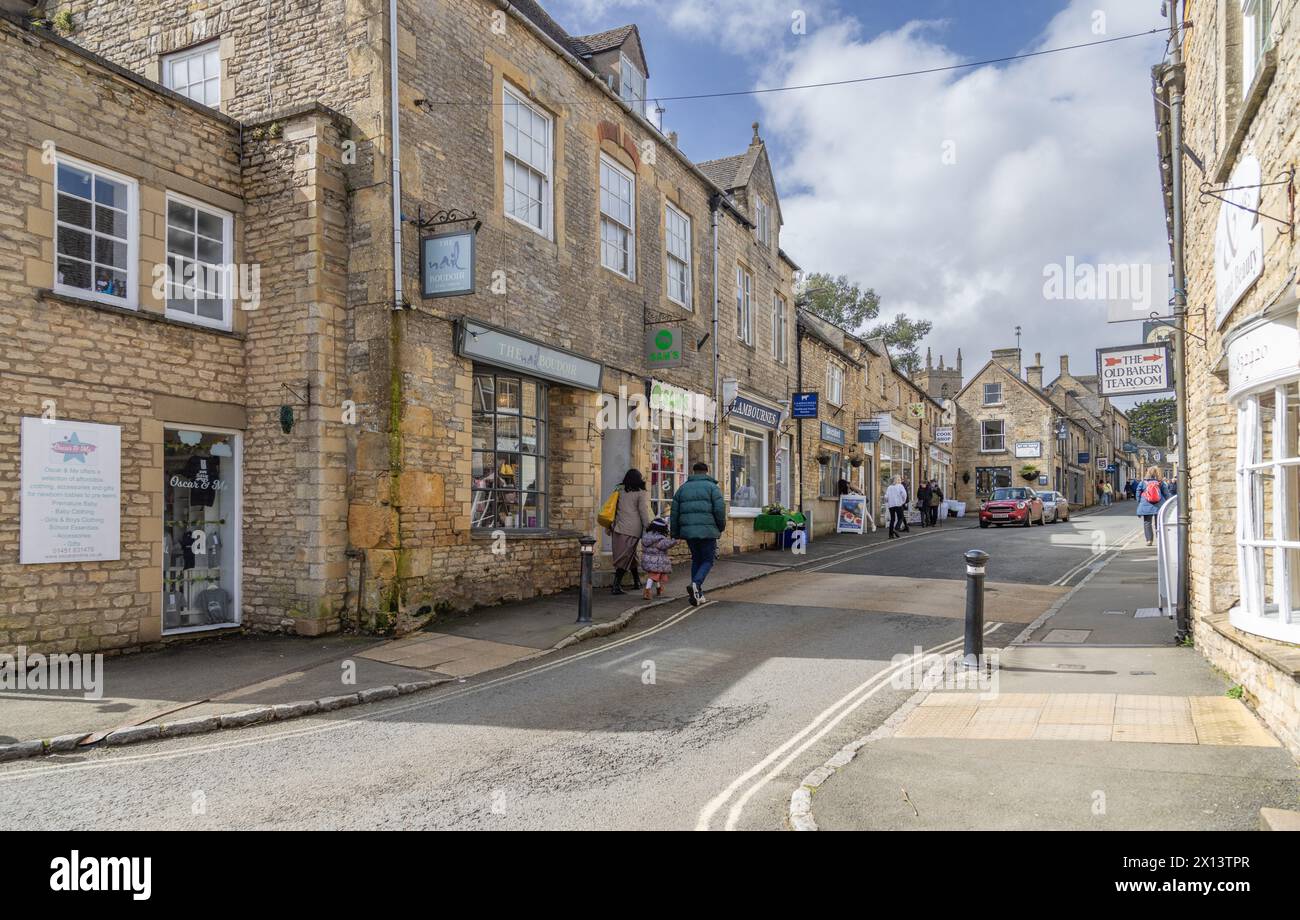 Tourists and shoppers strolling along a street lined with honey ...