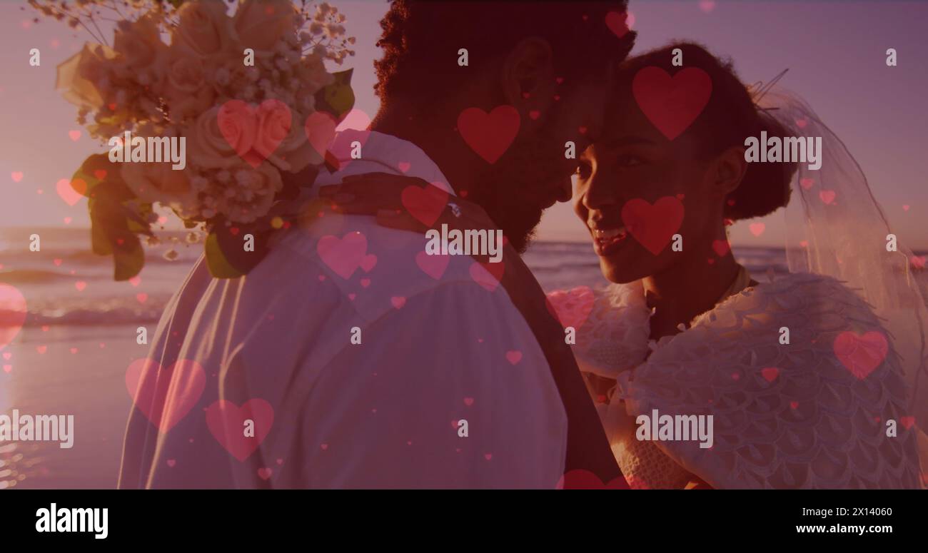 Red hearts floating against african american newly married couple ...
