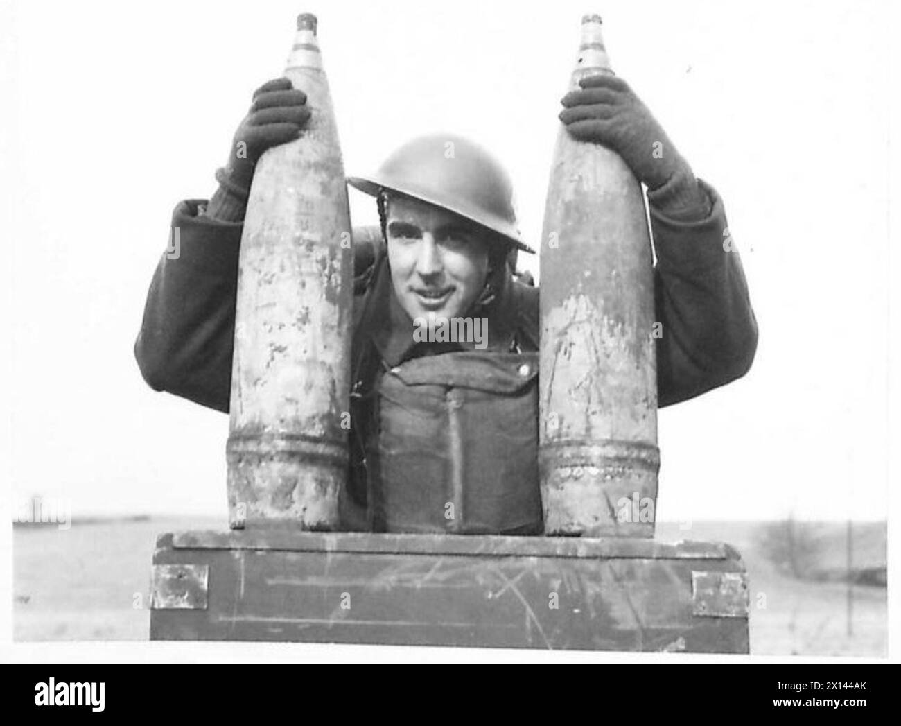 EXERCISES IN SCOTLAND - A gunner with a couple of six inch shells ...