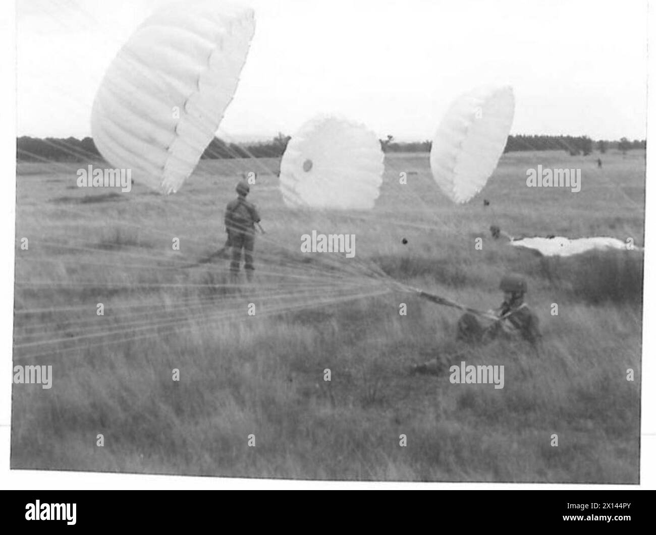Paratroops are shown managing their parachutes upon landing, moving ...
