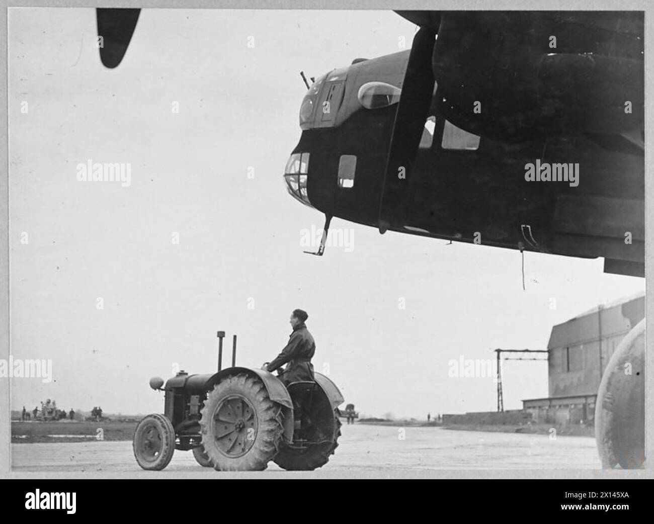Photograph showing a Royal Air Force tug maneuvering a Halifax bomber ...