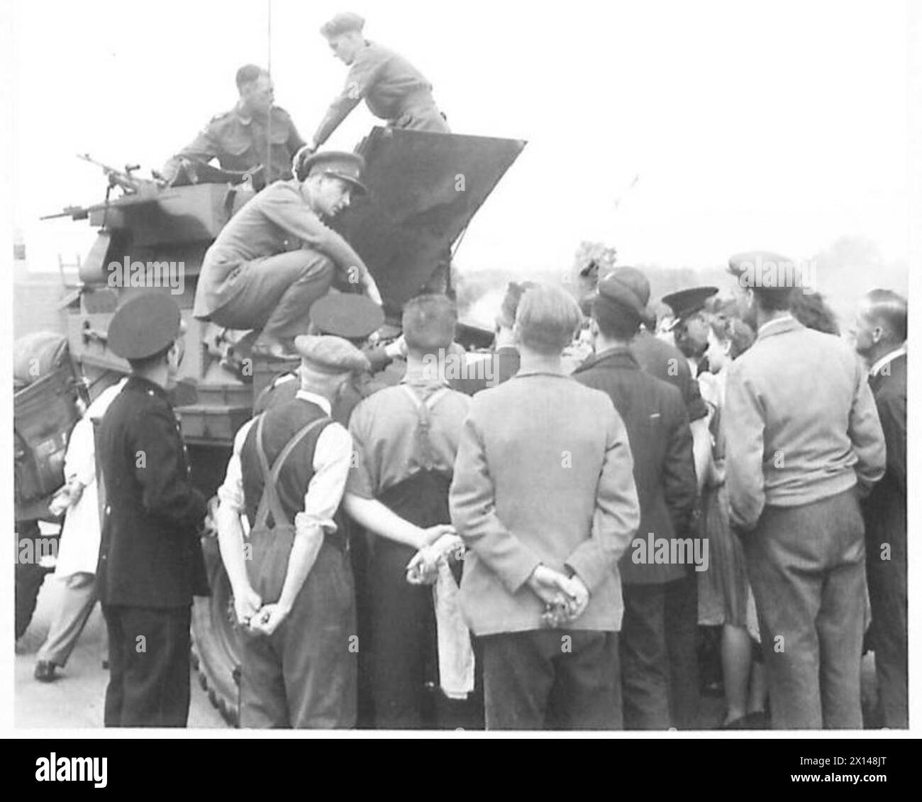 WORKERS INSPECT ARMOURED CAR - Factory workers gather round and listen ...