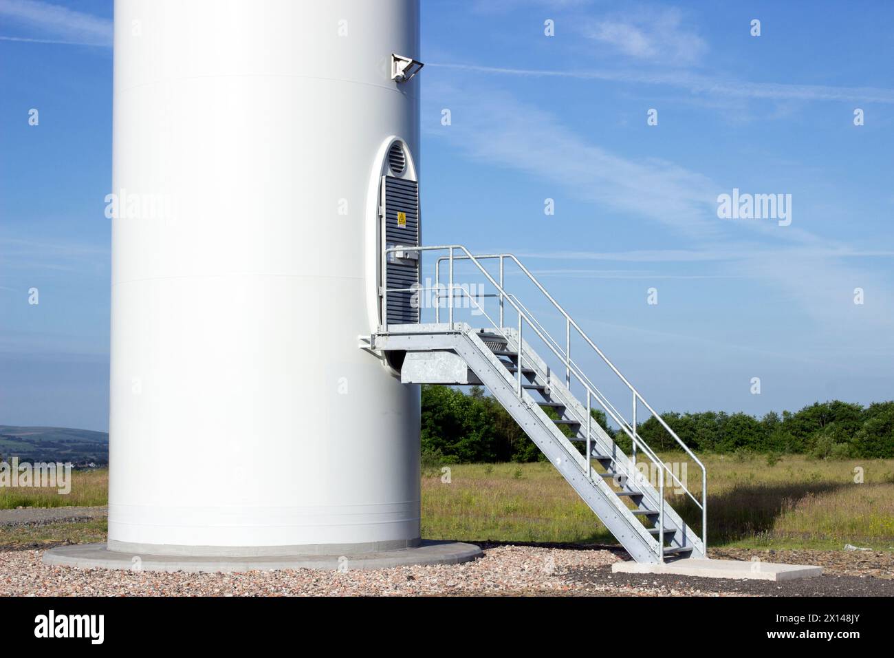 Wind turbine tower and access ladder against blue sky background ...