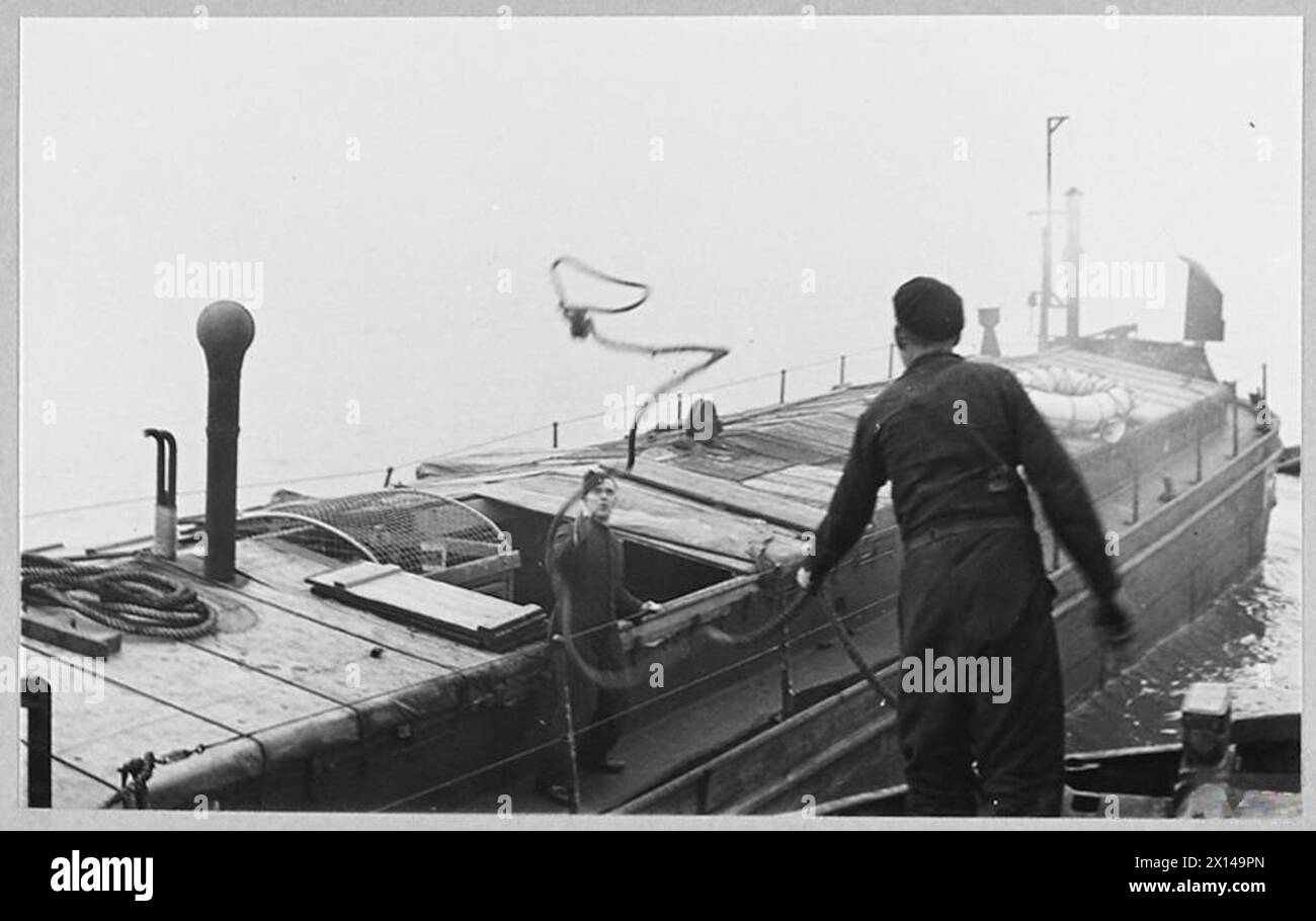 A barrage balloon is transferred from shore to the supply barge 'Norman ...