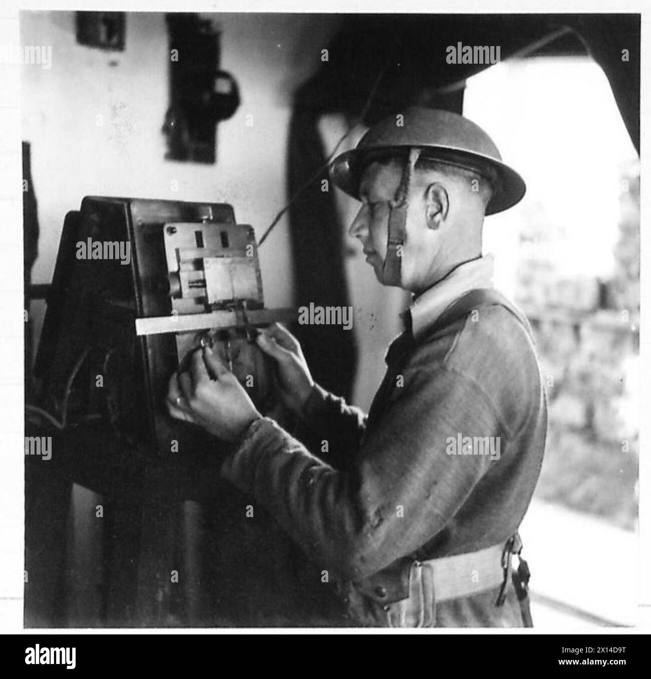 A gunner at the British coast battery in Lebanon uses a line correction ...