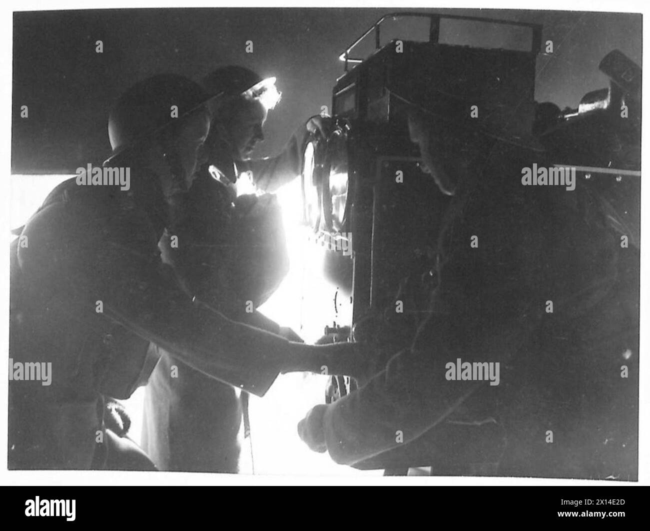 ATS anti-aircraft personnel operate a predictor at night, performing calculations and ...