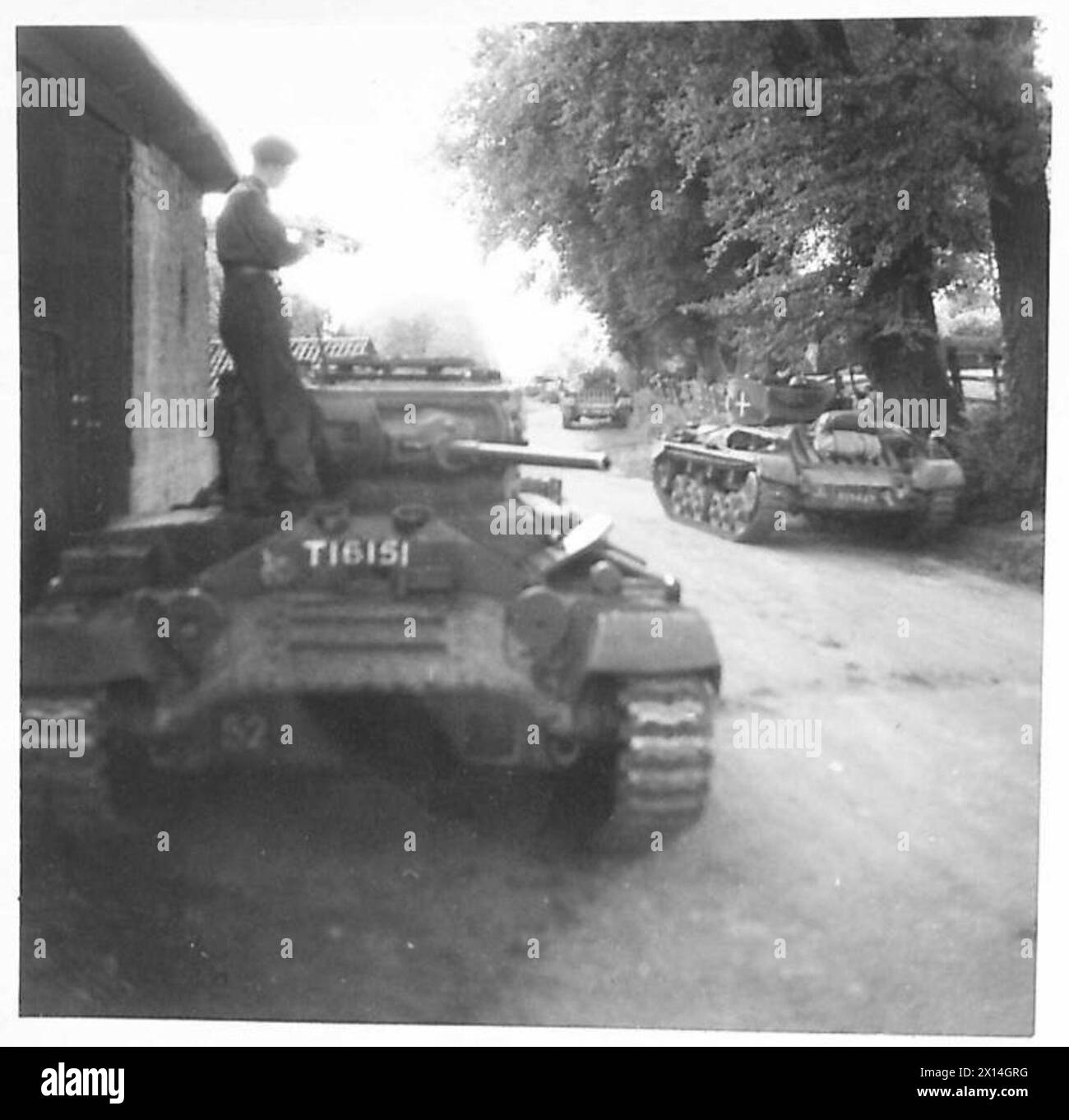 A British tank crew member stands guard with machine guns over captured ...
