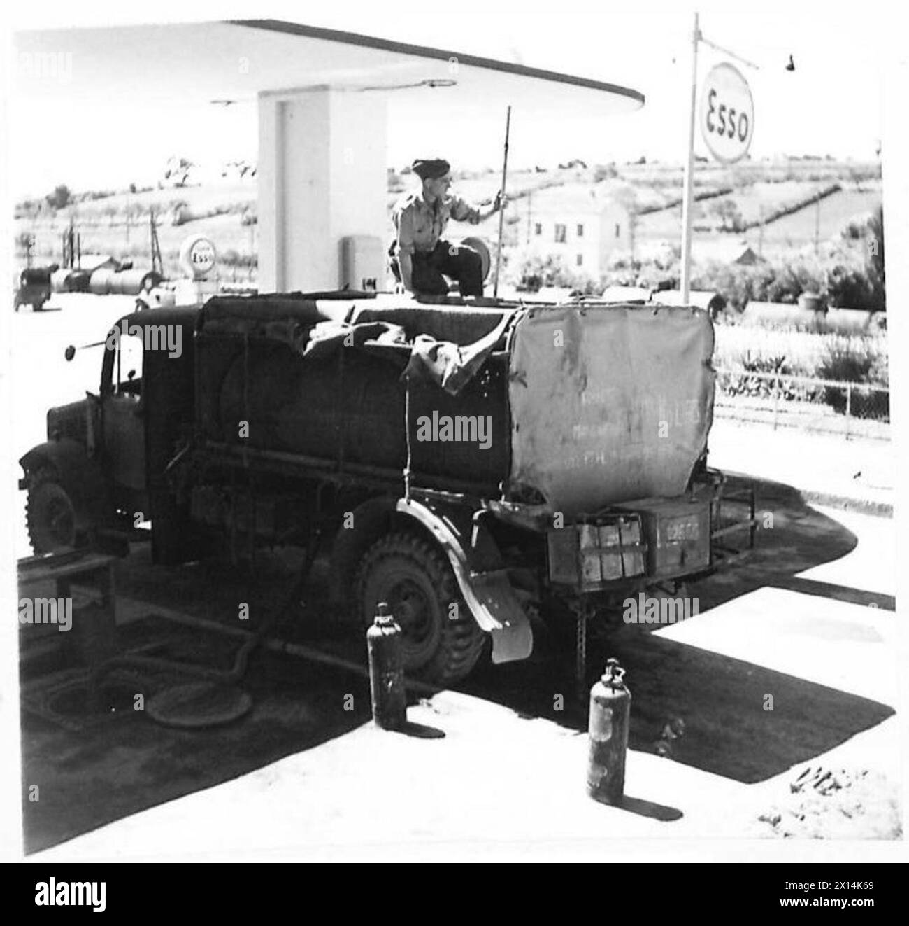 British Army personnel refuel vehicles at a roadside petrol pump ...