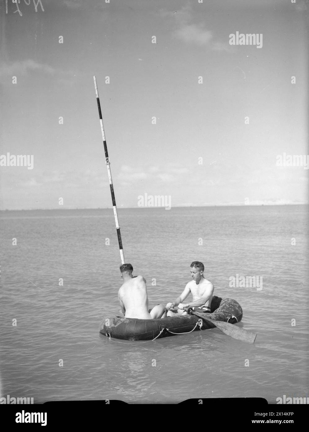 Two men take soundings from a rubber dinghy while naval beach parties ...