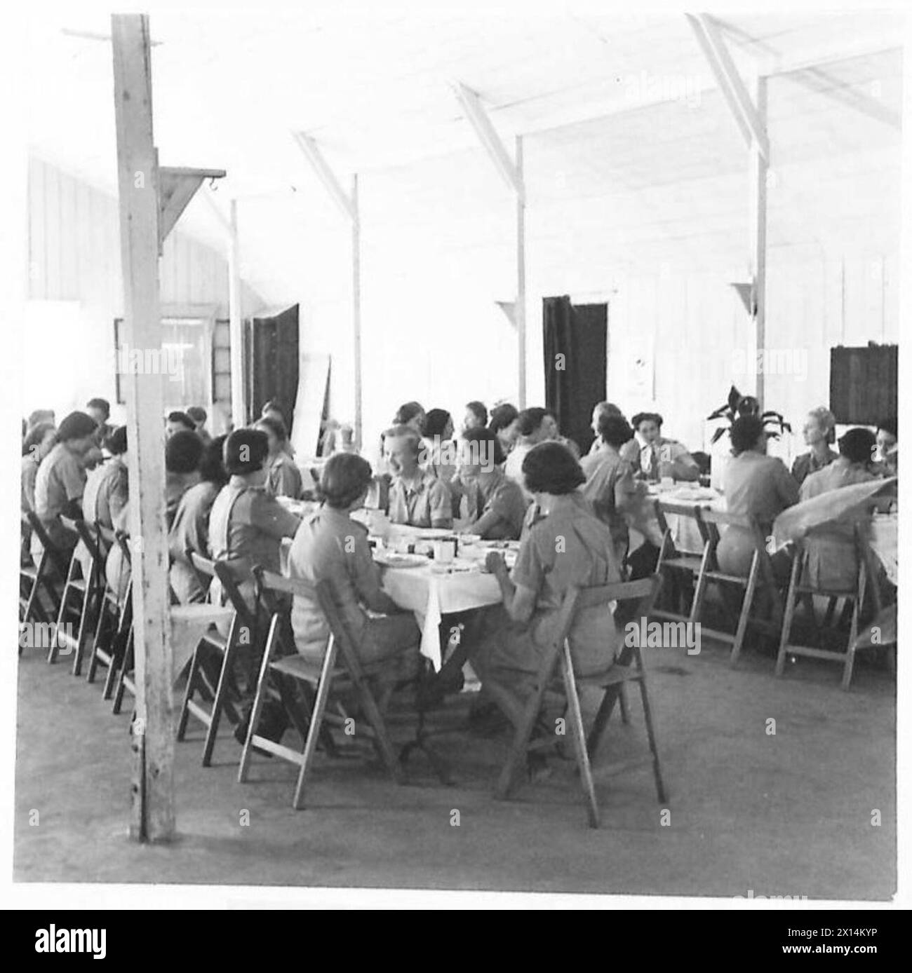 Women of the Auxiliary Services are shown in the desert camp mess room ...