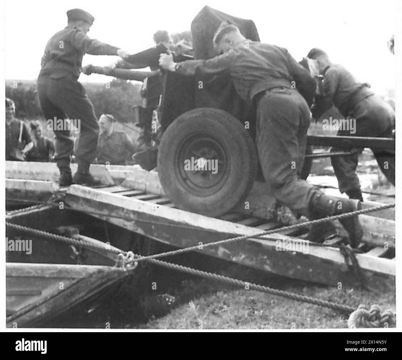 A 2-pounder anti-tank gun is loaded onto a pontoon ferry to be ...
