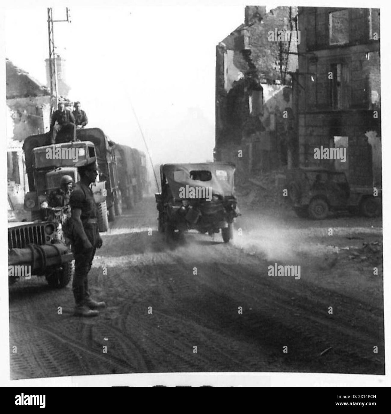 A Military Police officer directs a convoy of tanks and vehicles ...
