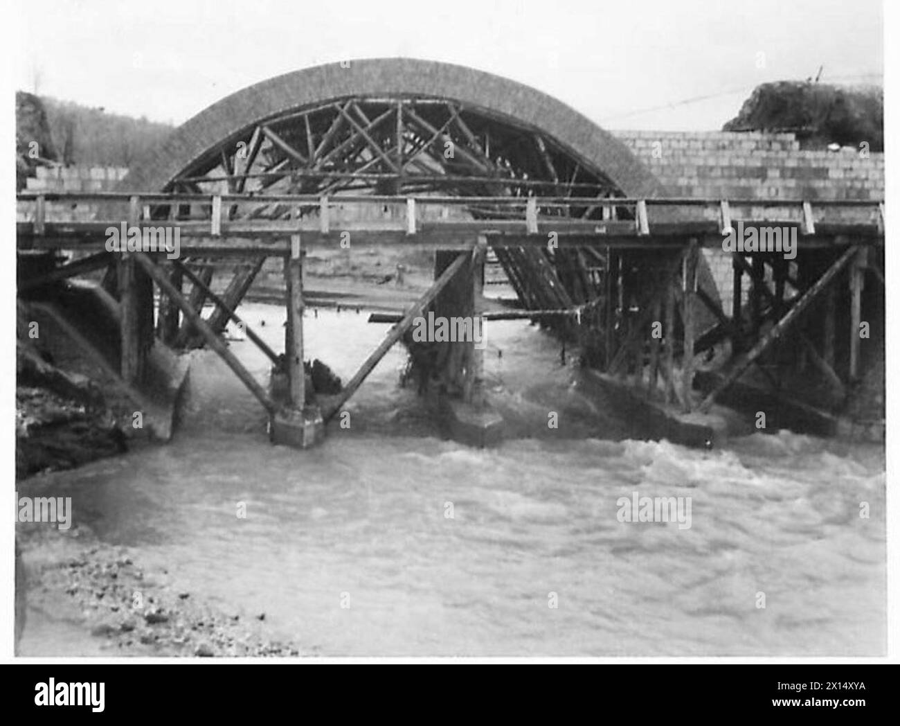 A timber temporary bridge with concrete piers, stone abutments, and ...