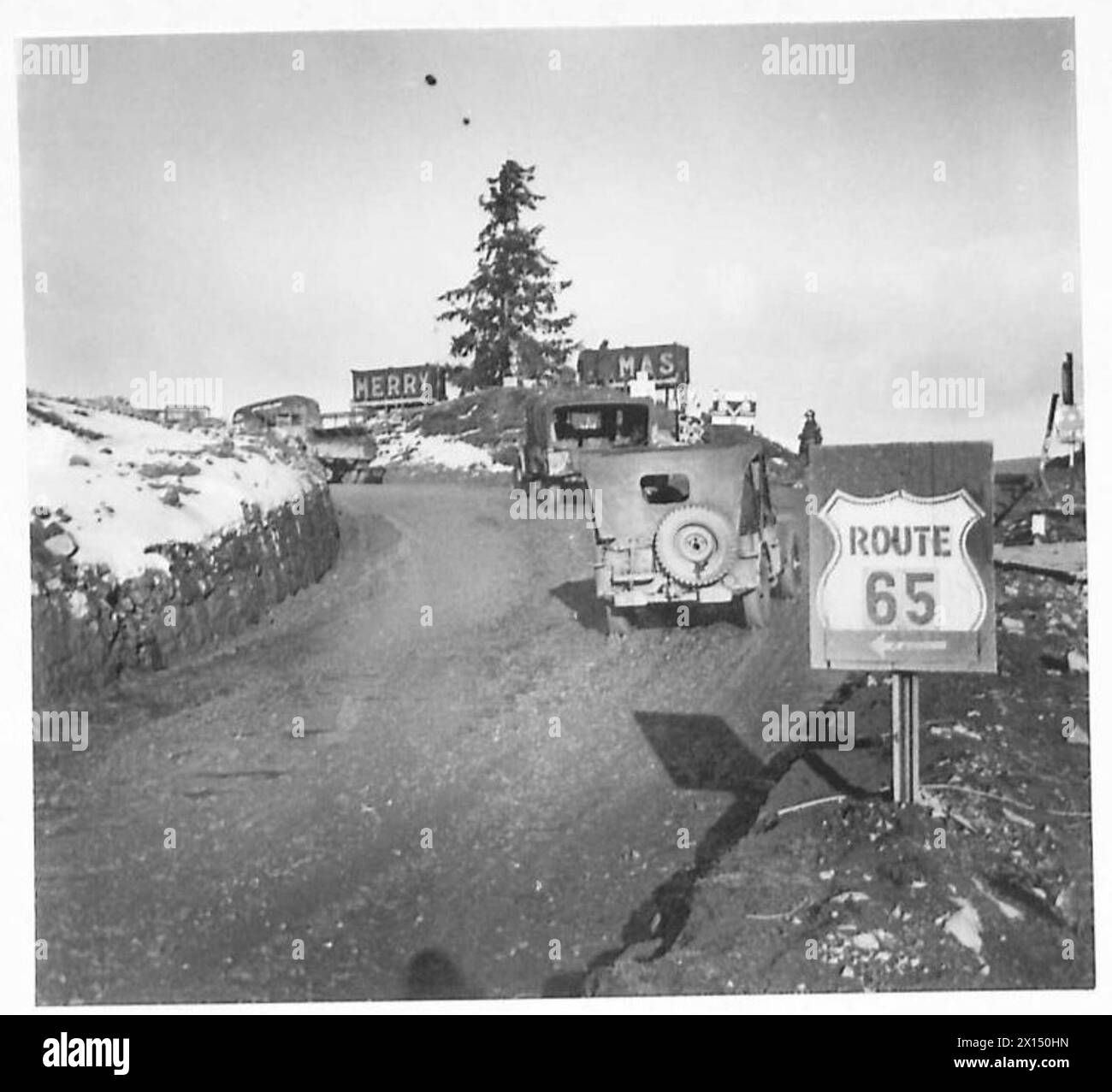 Military transport moves along Route 65 past a large Christmas tree and ...