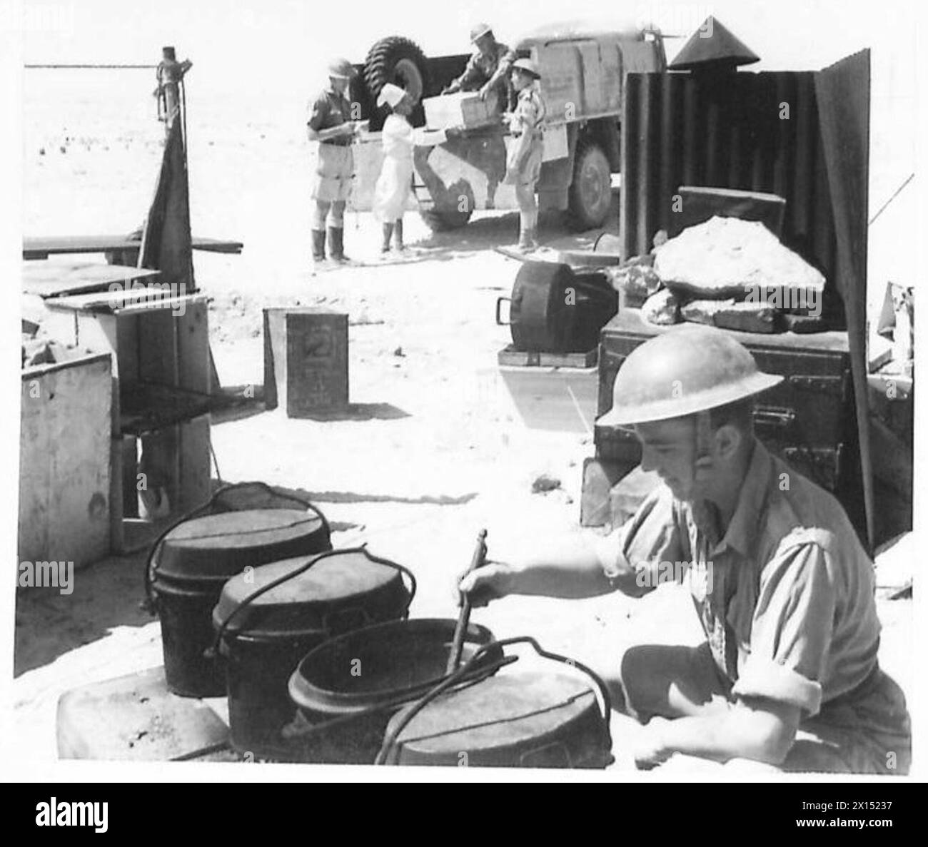 In a small desert camp, the cook collects daily rations from a truck ...