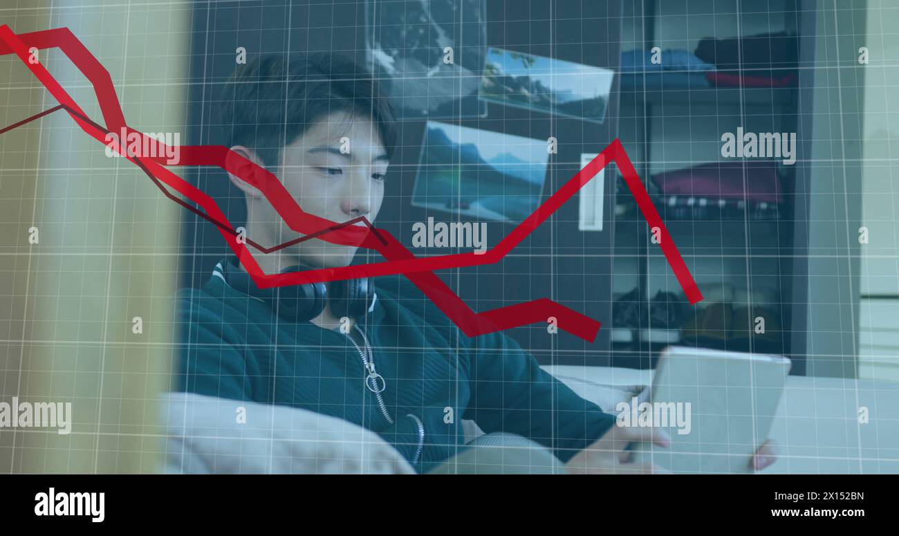 Image of multiple falling graphs over asian boy playing game on digital ...