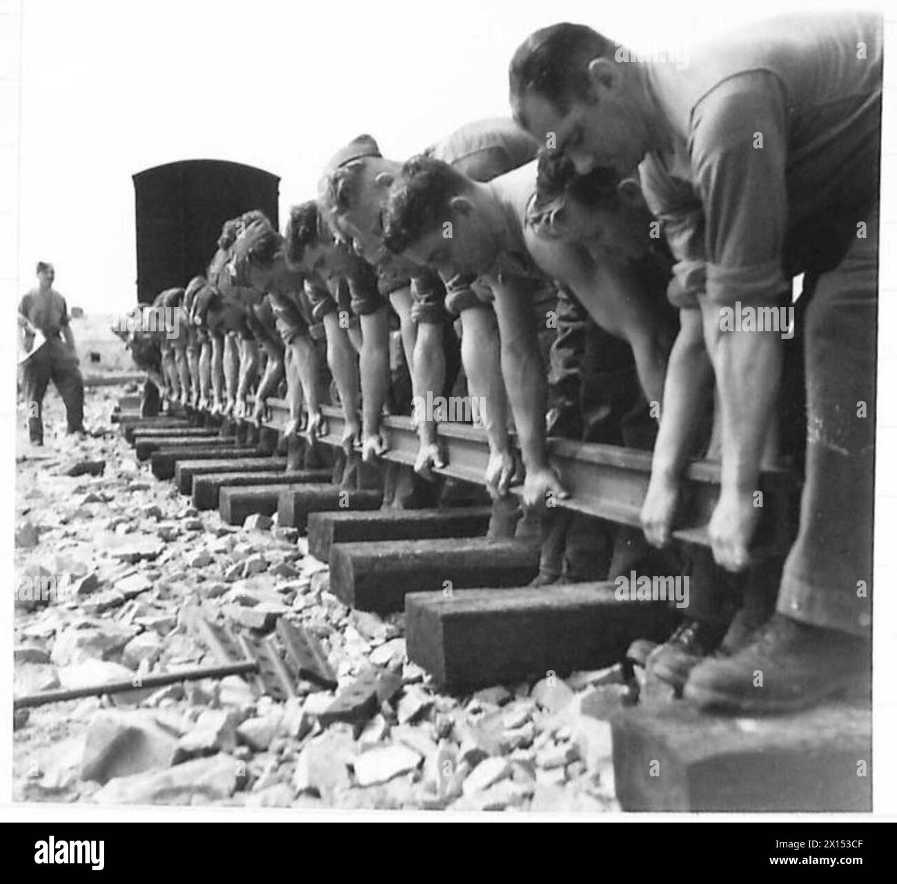 Army sappers are laying railway lines by lowering rails onto sleepers ...