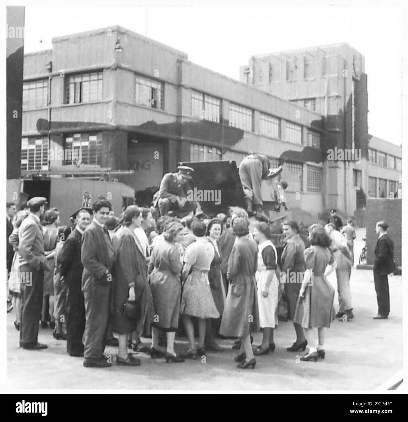 WORKERS INSPECT ARMOURED CAR - Factory workers gather round and listen ...