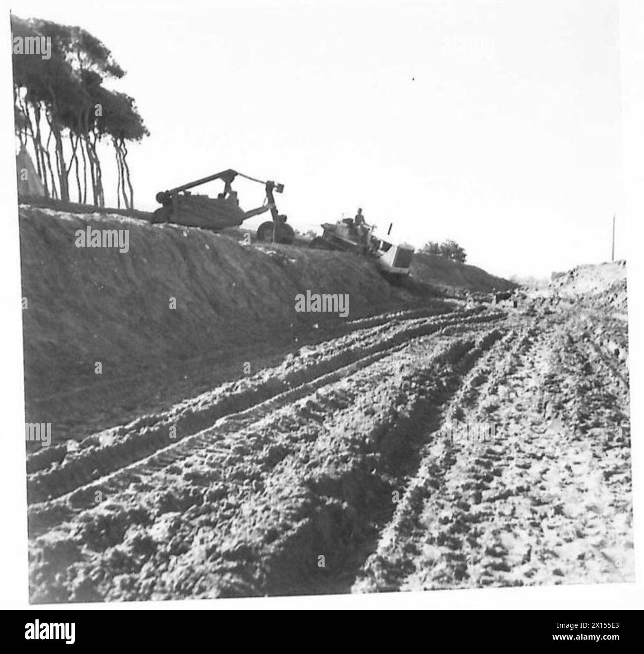 A Carryall Scraper, hauled by a caterpillar tractor, makes a cutting ...