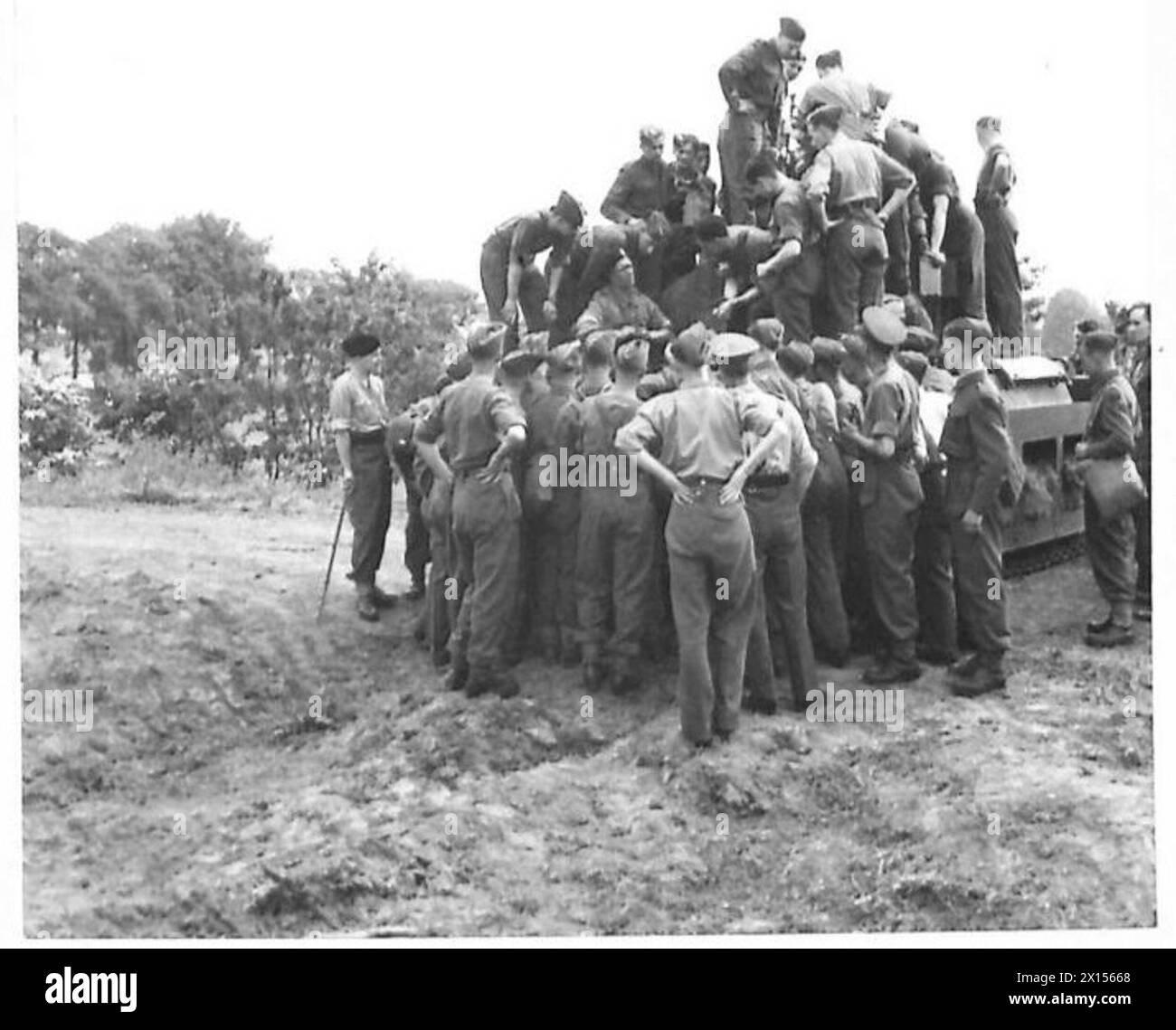 A group of men observes a tank demonstration while a lecturer explains ...