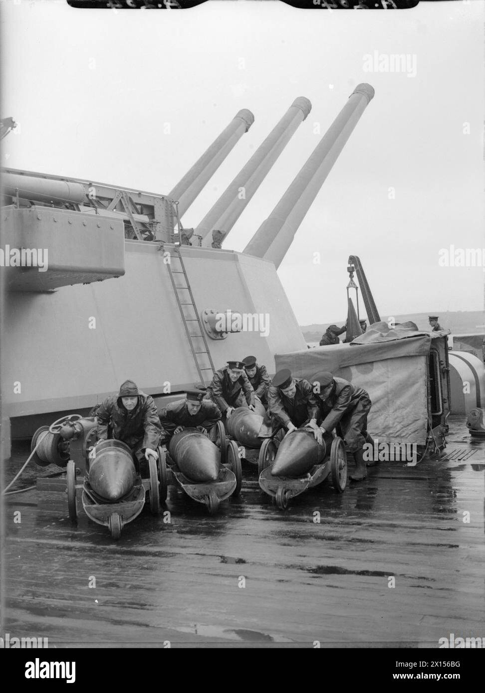 16-inch shells are wheeled on board HMS Rodney from an ammunition ship ...