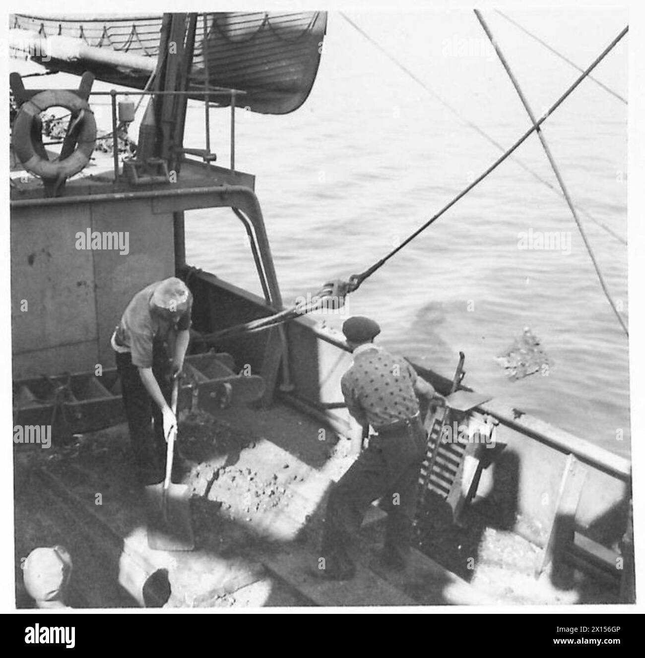 ON BOARD AN AFRICAN BOUND SHIP IN CONVOY - Fireman clearing ashes from ...