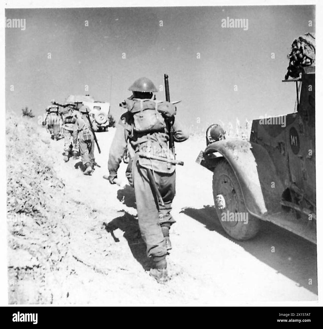 Infantry and armoured vehicles of the British Army advance along a ...