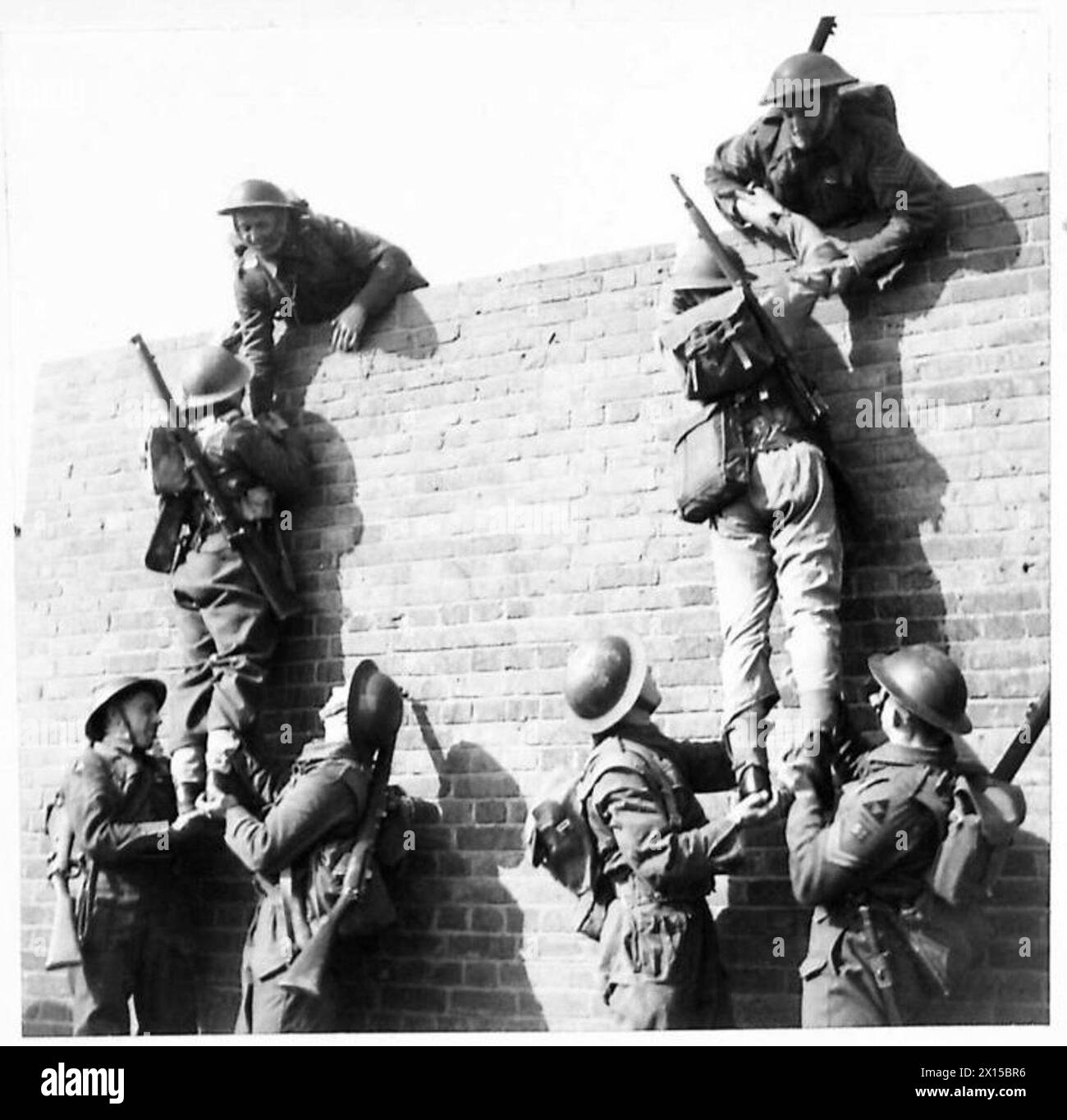 British Army personnel practice climbing a ten-foot wall using a ...