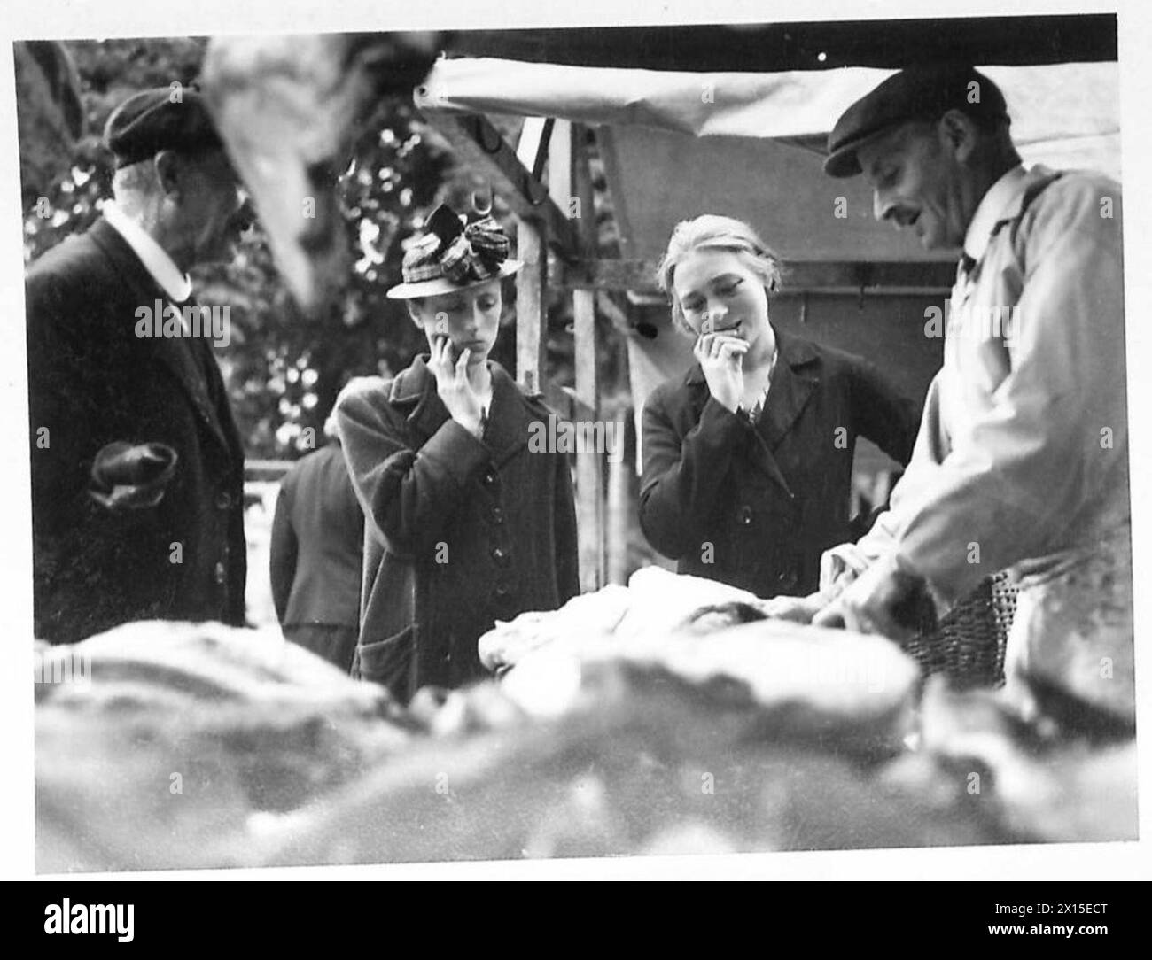 Purchasers observe the butcher's stall during a market scene in British ...
