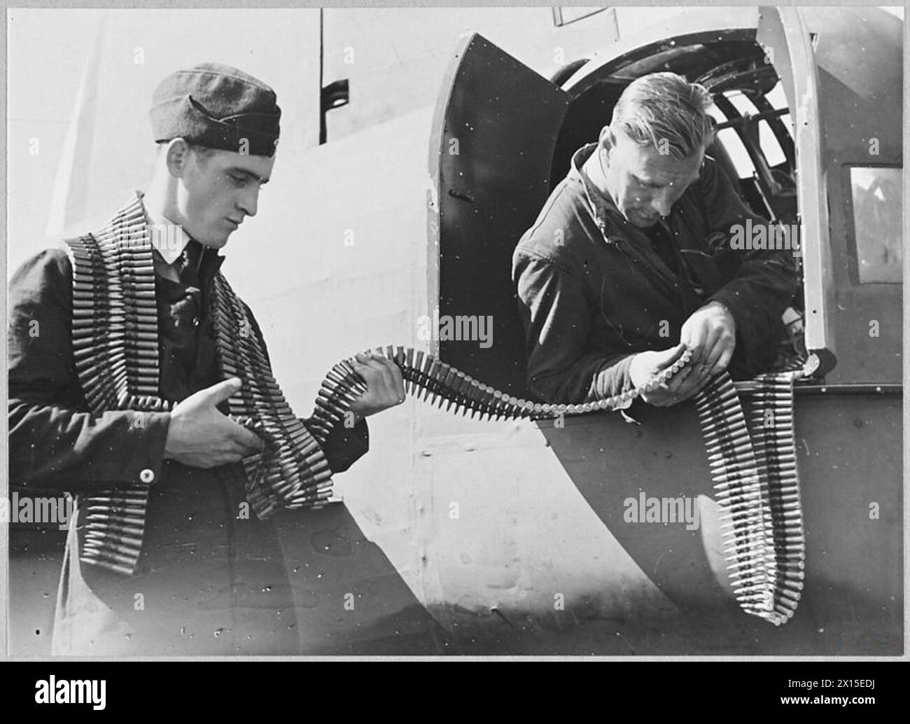 THE MEN BEHIND THE MACHINES - Armourers feed in ammunition belts for ...