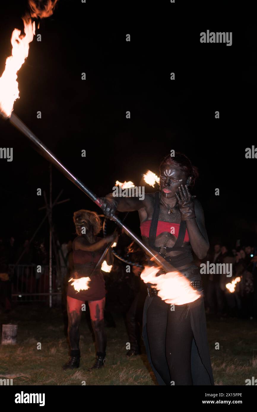 fire dancer with a torches alight at each end swinging fire that ...