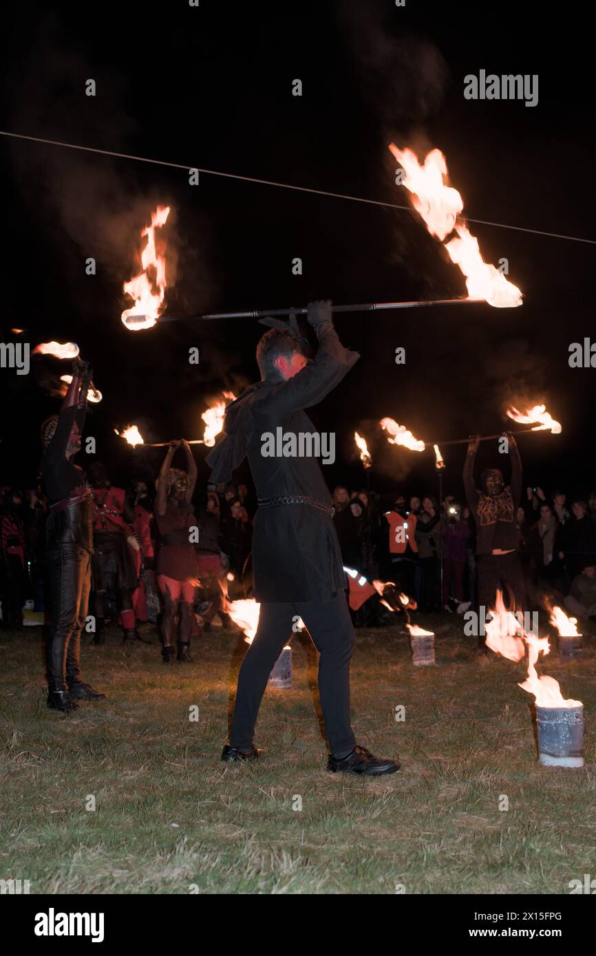 fire show performer with a stick alight at each end twirling fire that ...