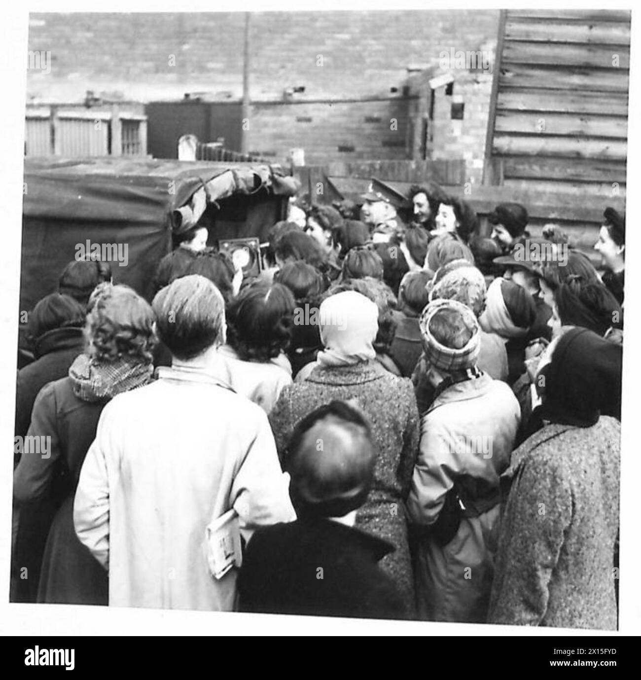 ARMY VISIT WIRELESS FACTORY WORKERS - Factory workers crowd round a ...