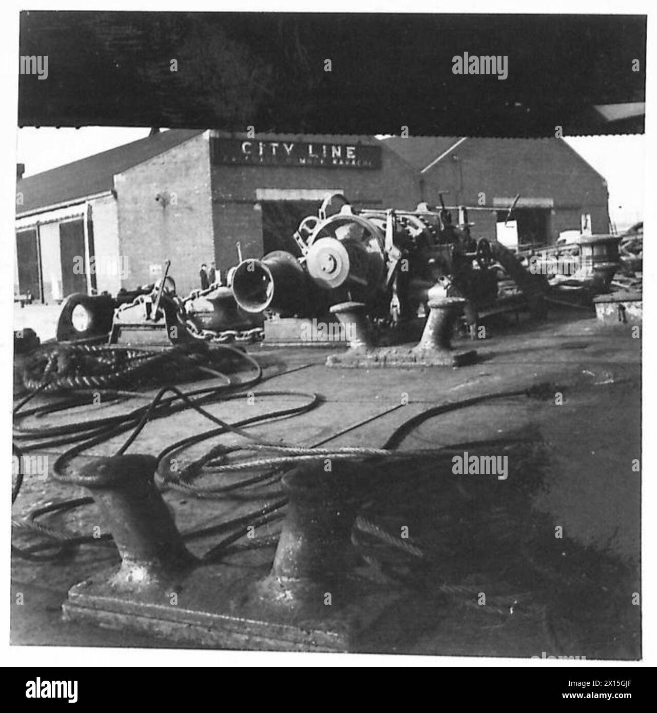 British and American troops embark at a dockside using winches for ...
