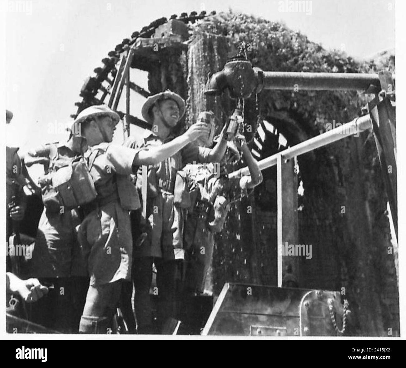 British troops in Syria fill water bottles at an ancient water point ...