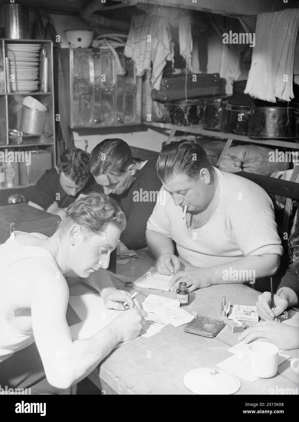 Seamen write letters on board the Hunt class destroyer HMS Garth, which ...