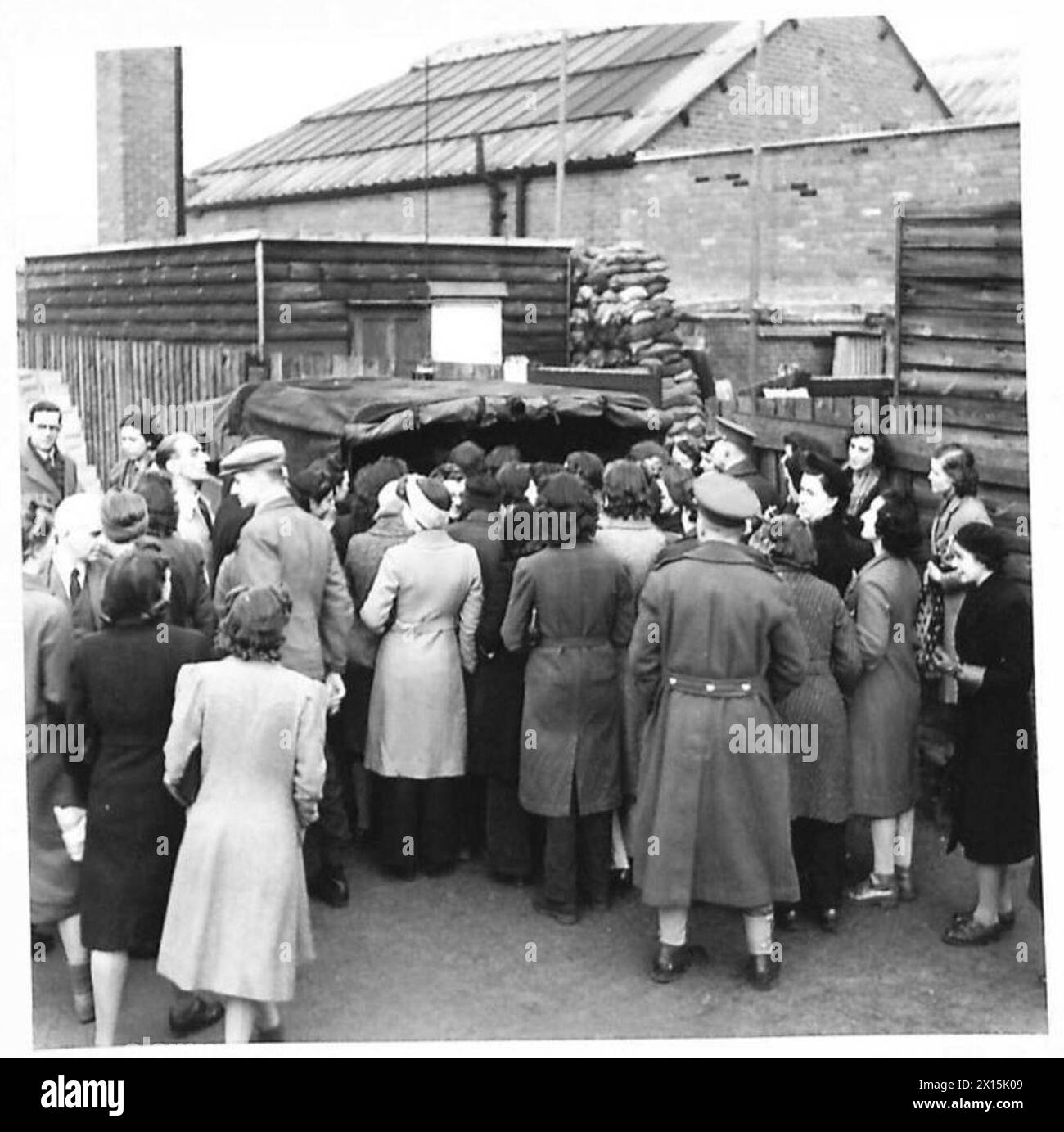 ARMY VISIT WIRELESS FACTORY WORKERS - Factory workers crowd round a ...