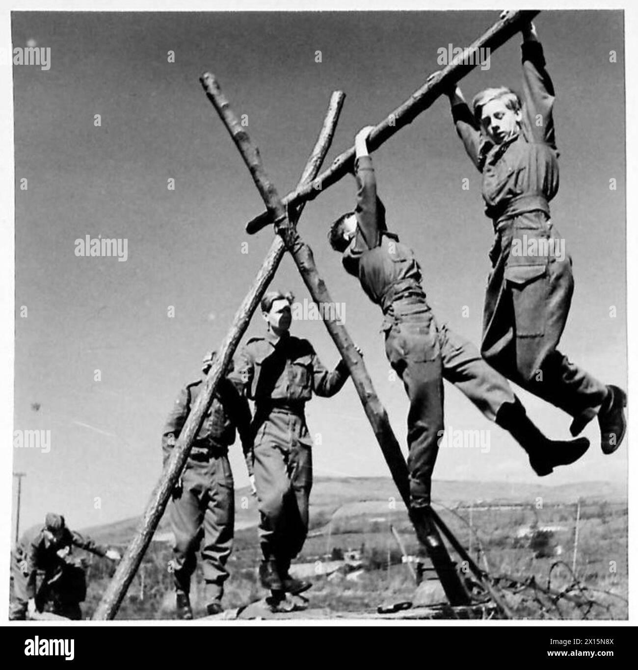 Young British Army soldiers cross a barbed wire entanglement using the ...