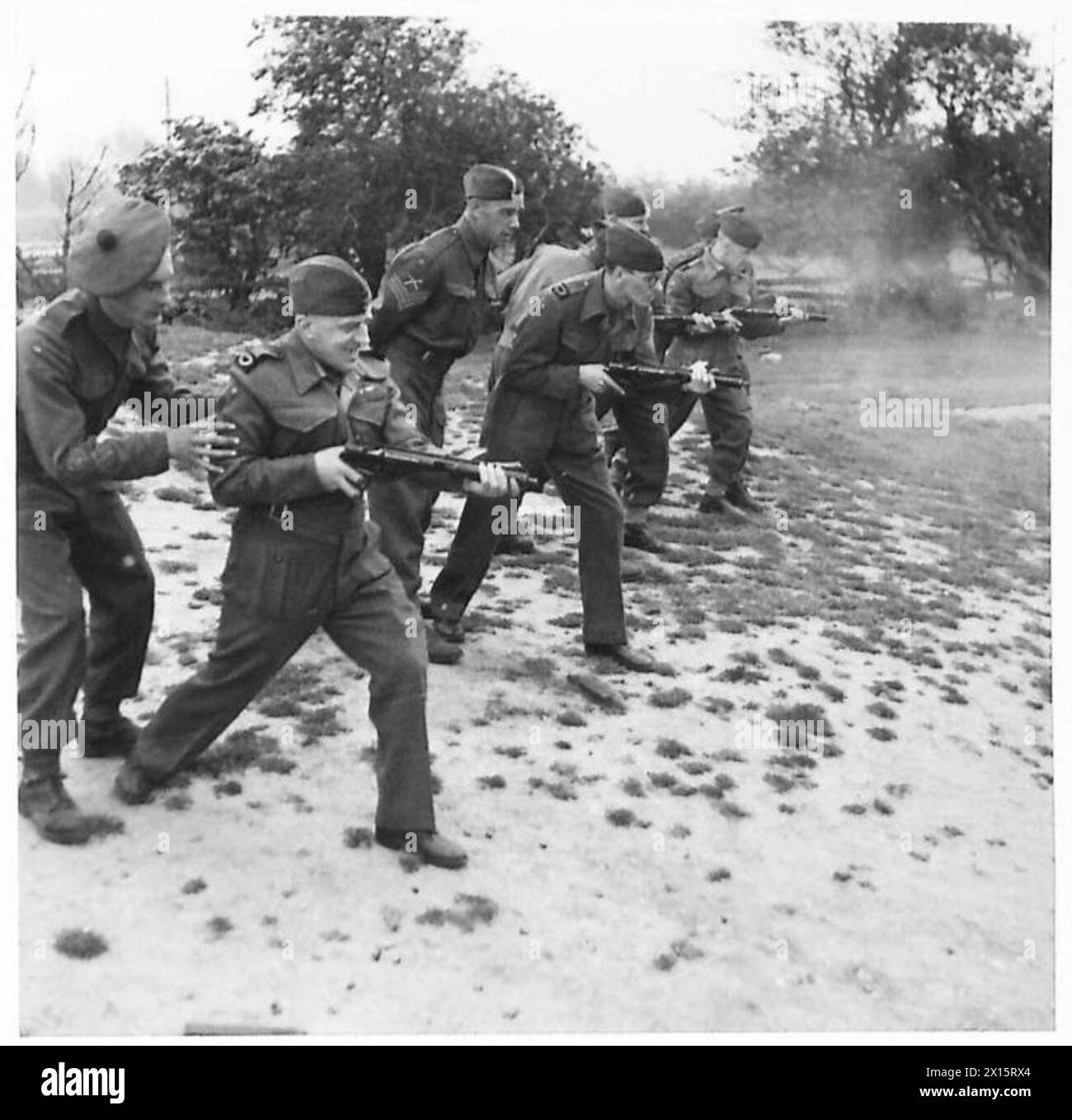 War correspondents fire Sten guns on the training range under the guidance of weapons school ...