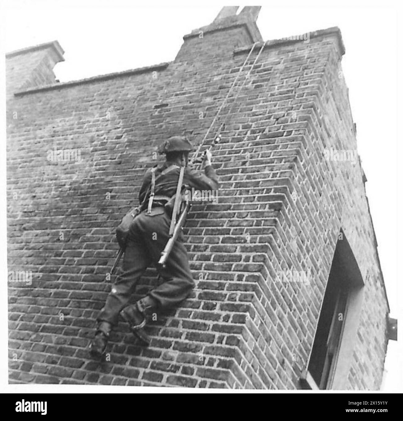 A trainee demonstrates rope techniques for scaling the side of a house ...