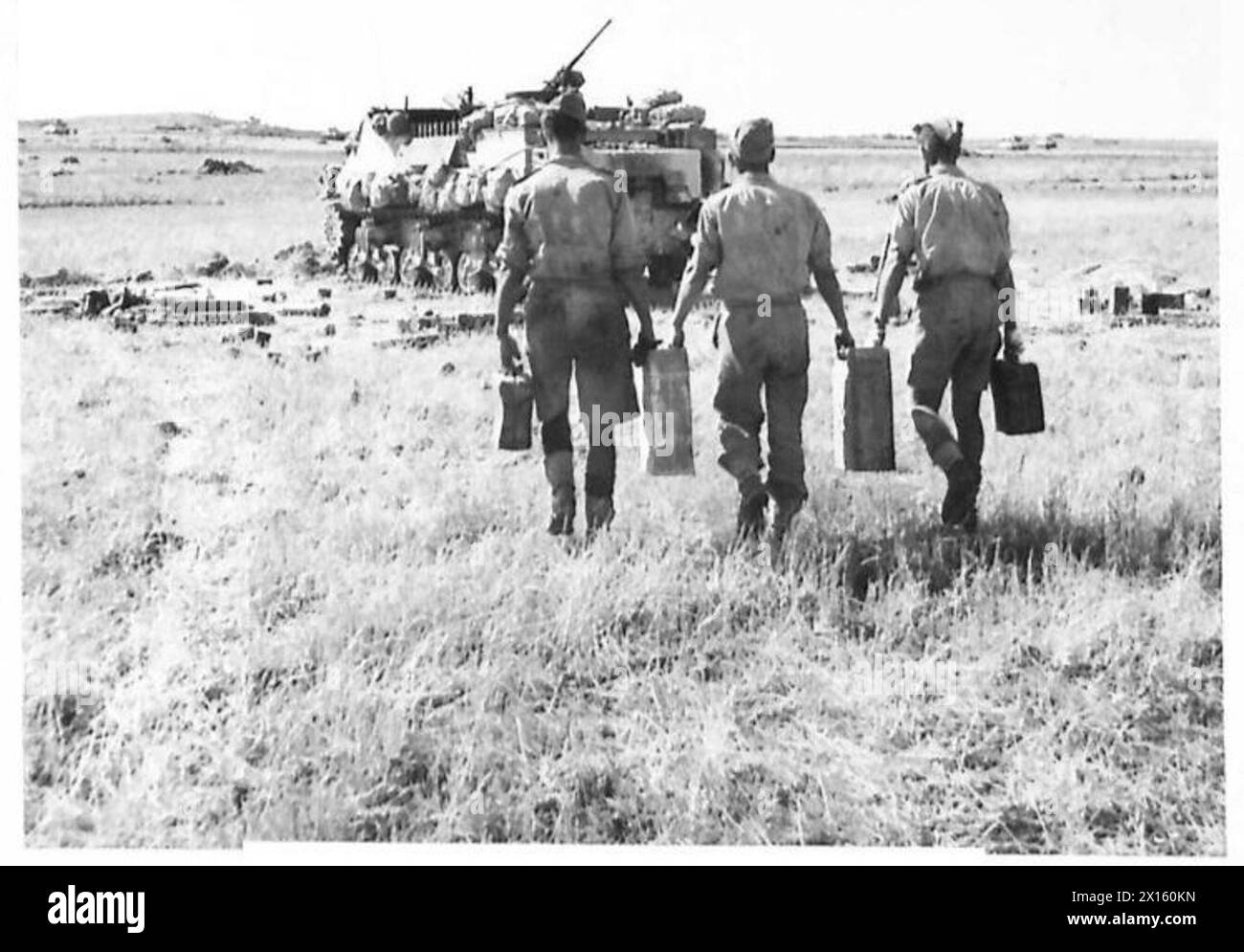 Crew members of a 'Priest' artillery vehicle return to their vehicle ...
