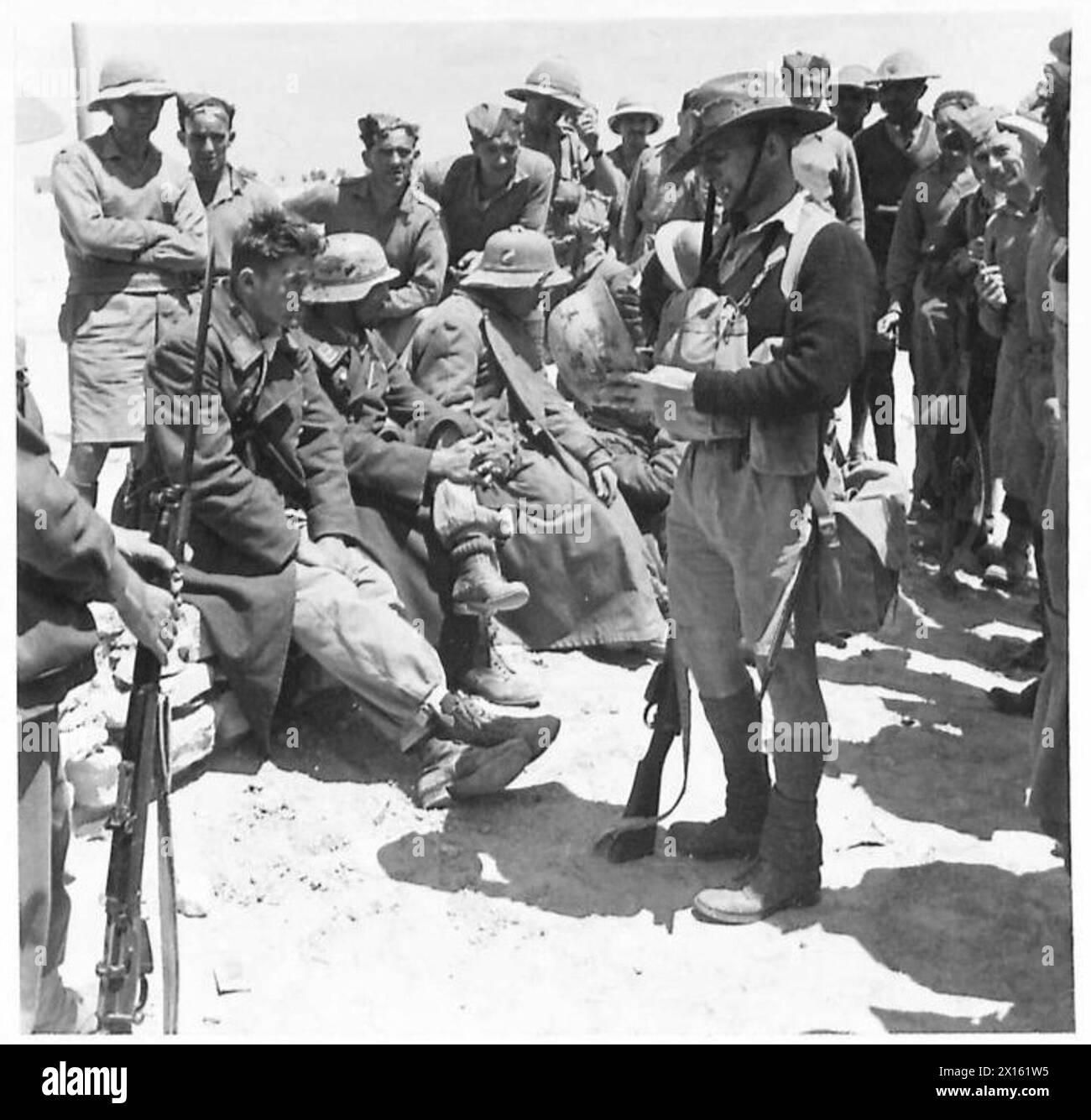 An Australian soldier examines the steel helmet of a German prisoner ...