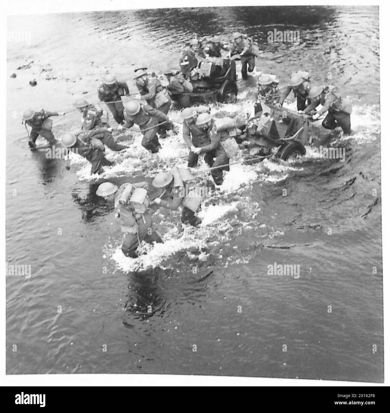 Soldiers haul anti-tank guns across a river during a military operation ...